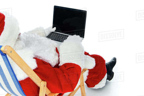 santa claus using laptop with blank screen while resting on beach chair ...