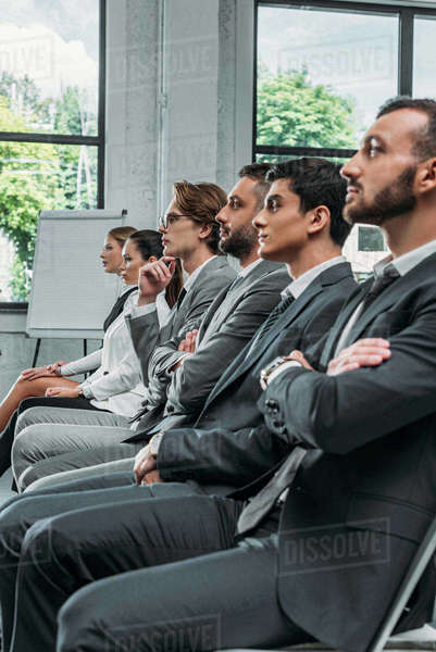 side view of businesspeople sitting on chairs during training in hub ...