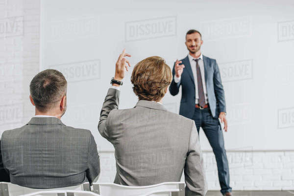 back view of businessman rising hand to coach during training in hub ...