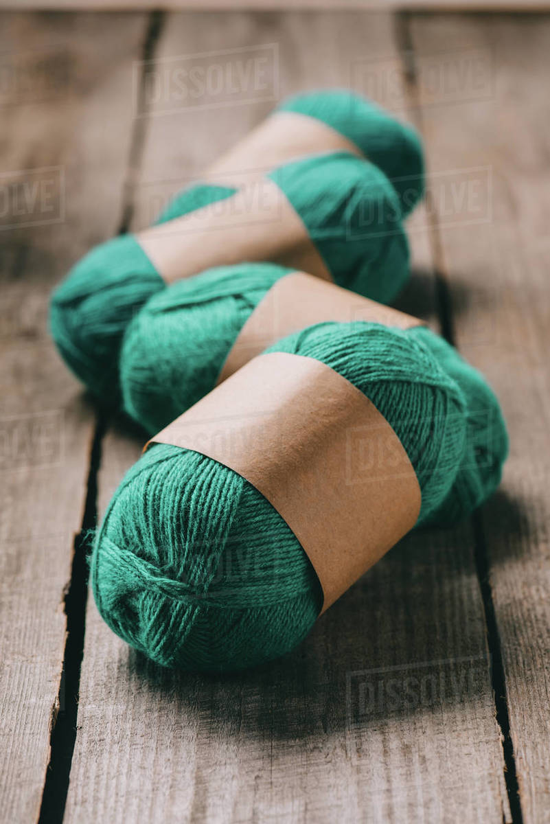 Selective focus of wrapped green knitted yarn on wooden background ...