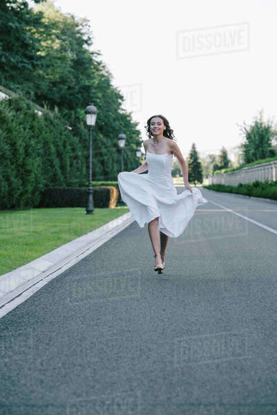 Beautiful happy bride in wedding dress running on road - Royalty-free ...