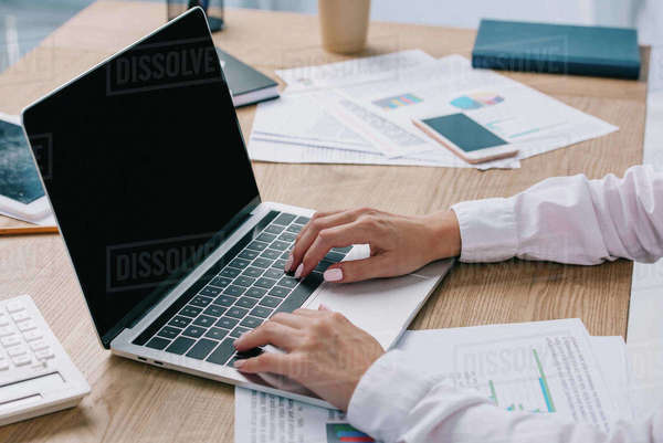 Partial view of businesswoman working on laptop with blank screen at ...