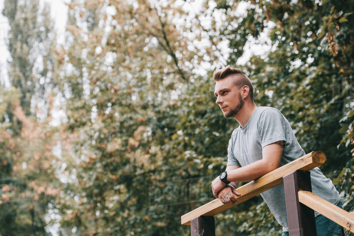 Handsome pensive man leaning on railings in park - Royalty-free Stock ...