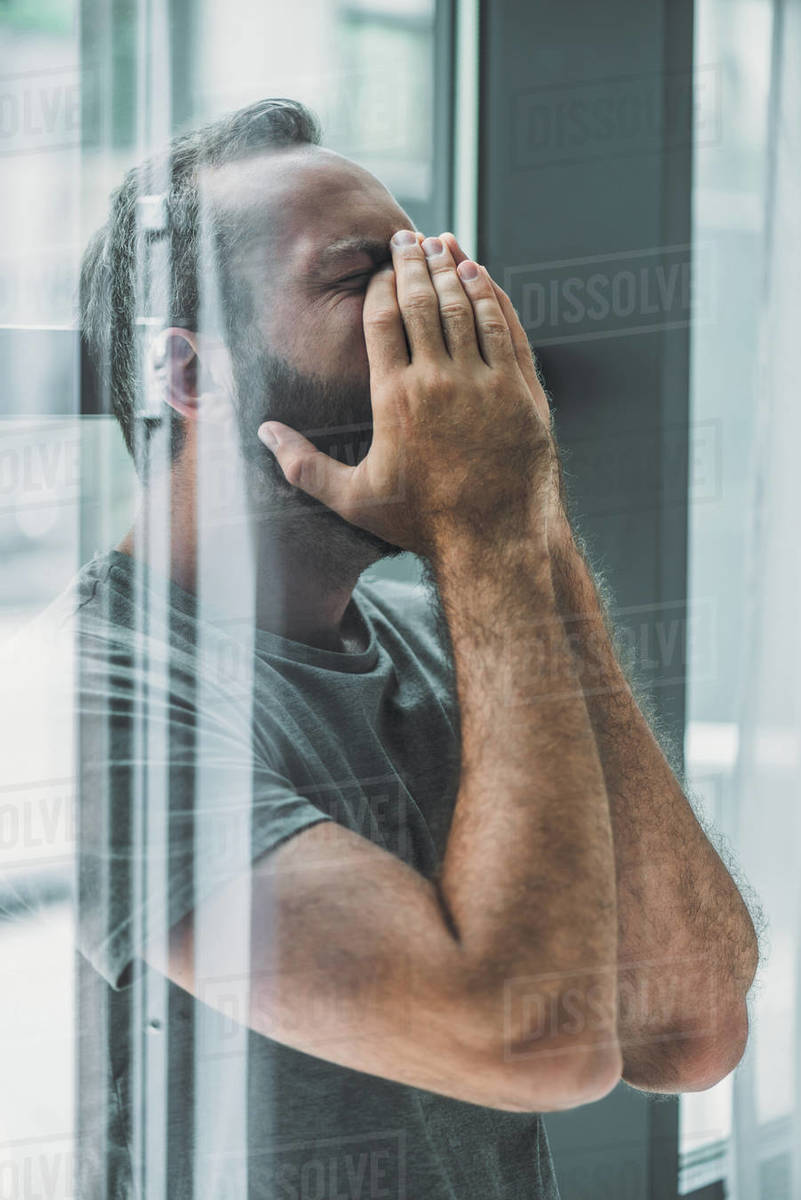 Side view of depressed frustrated bearded man crying with hands on face ...