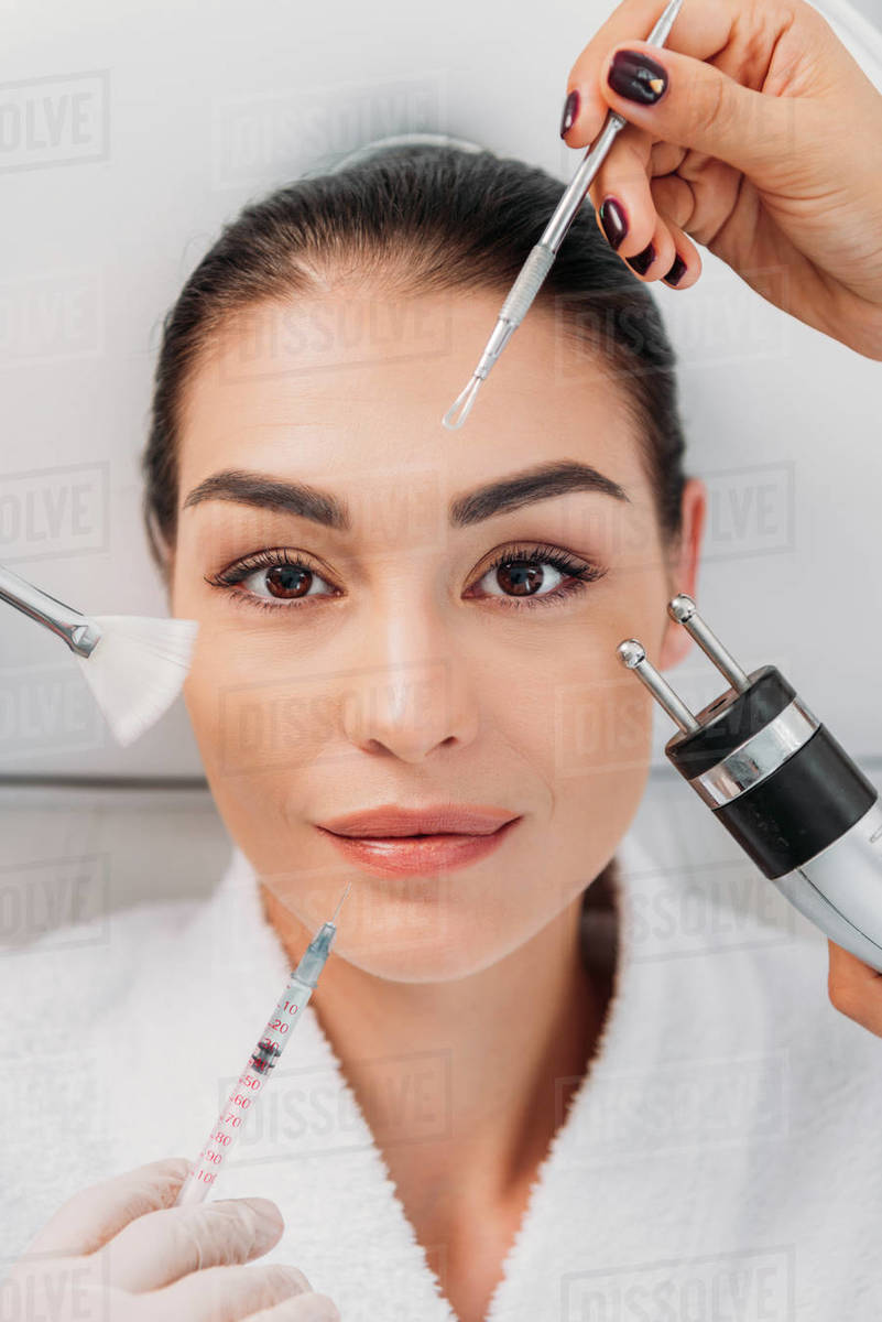 Overhead view of woman with various facial treatment equipment around ...