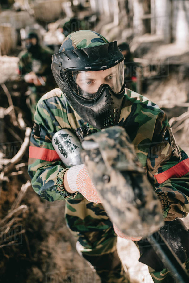 Selective focus of male paintball player in goggle mask and camouflage ...