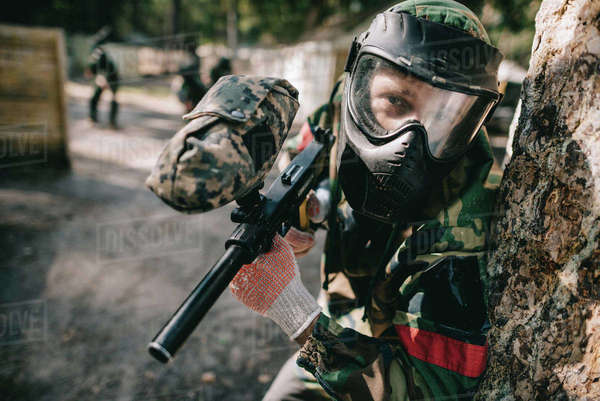 Selective focus of male paintball player in goggle mask and camouflage ...