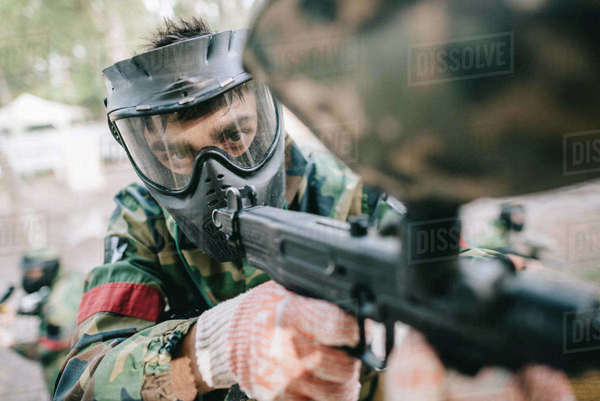 Selective focus of male paintball player in goggle mask and camouflage ...