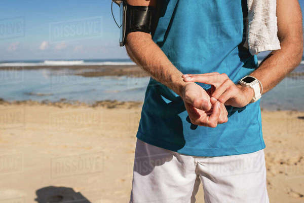 Cropped view of sportsman counting pulse on wrist after training ...