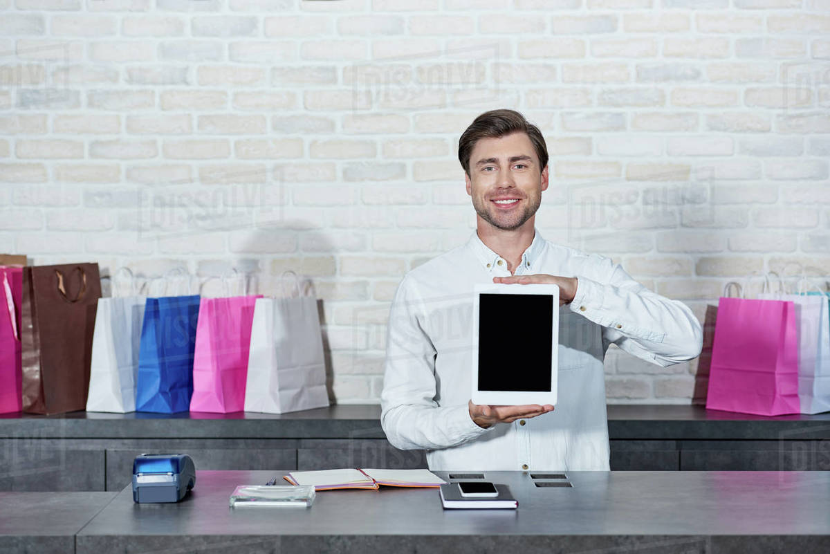 Handsome young salesman holding digital tablet with blank screen and ...