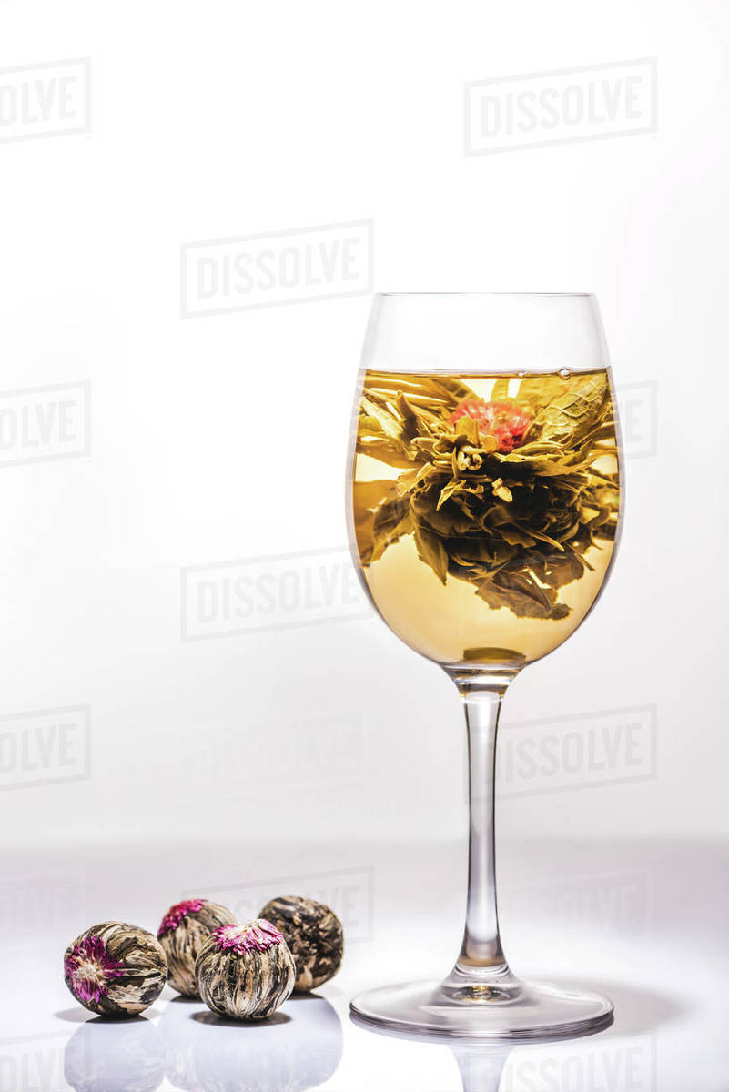 Beautiful glass of chinese flowering tea with tea balls on table ...