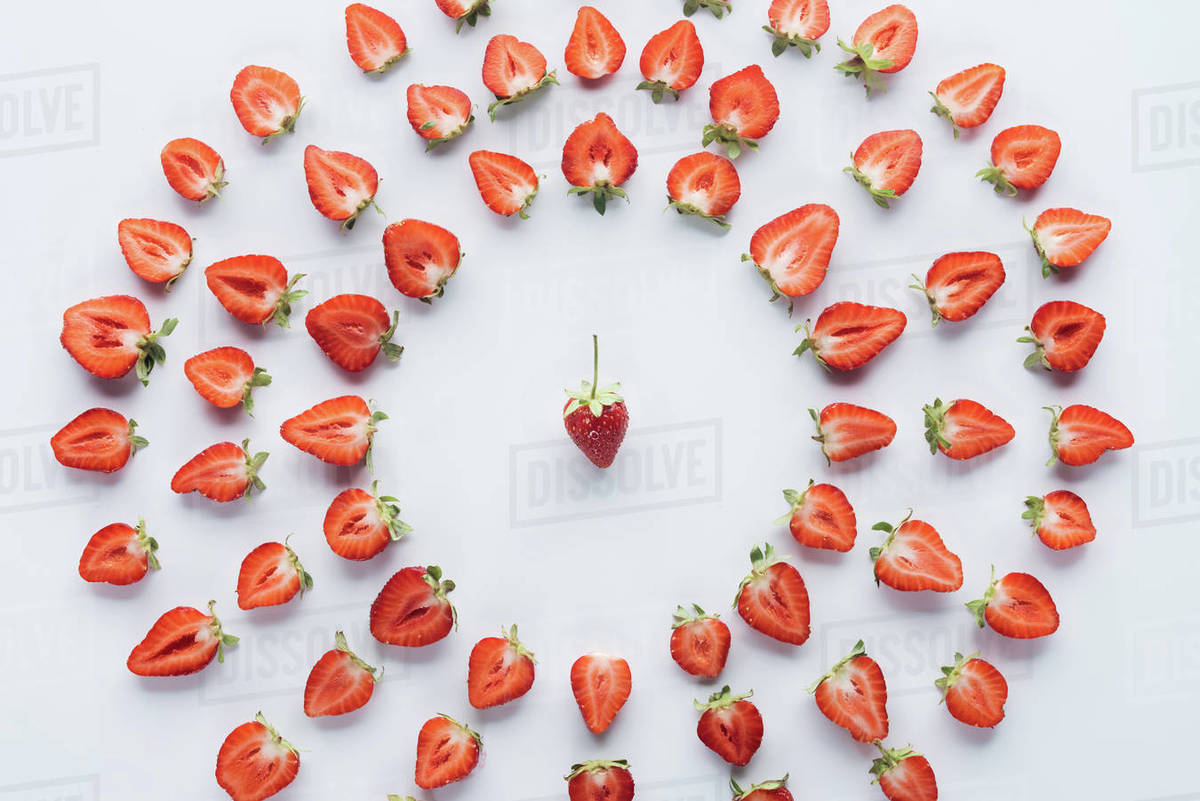 Top view of round frame of halved strawberries with whole in middle on ...