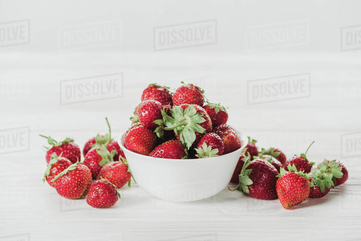 Close-up shot of bowl of strawberries on white wooden tabletop - Stock ...
