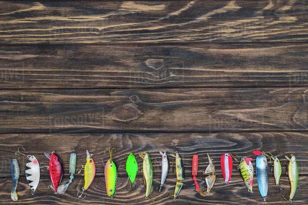 Top view of various fishing bait placed in row on wooden background ...