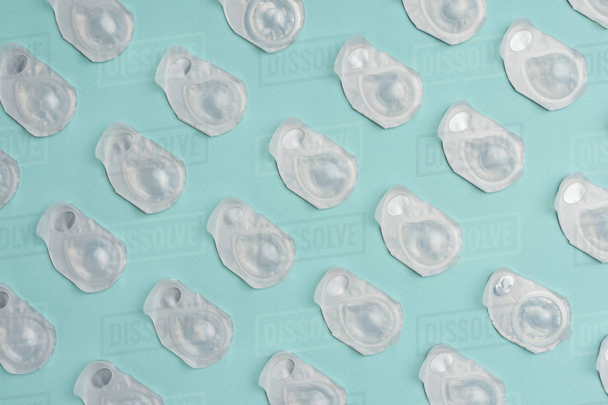 Full frame of contact lenses in containers arranged on blue background ...