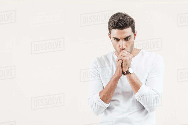 Focused young man thinking and looking down isolated on beige - Royalty ...
