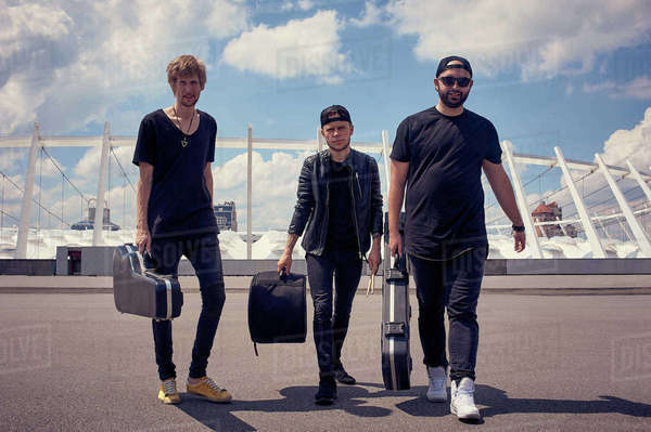 Young musicians with musical instruments in cases walking on street ...