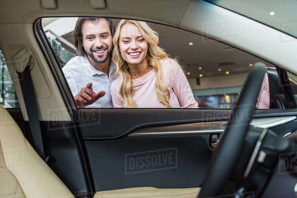 Smiling couple looking into new car at dealership salon - Royalty-free ...