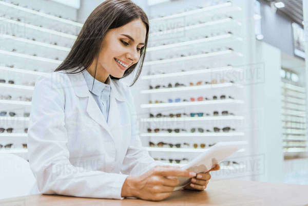 Professional smiling optician using tablet in Optica - Stock Photo ...