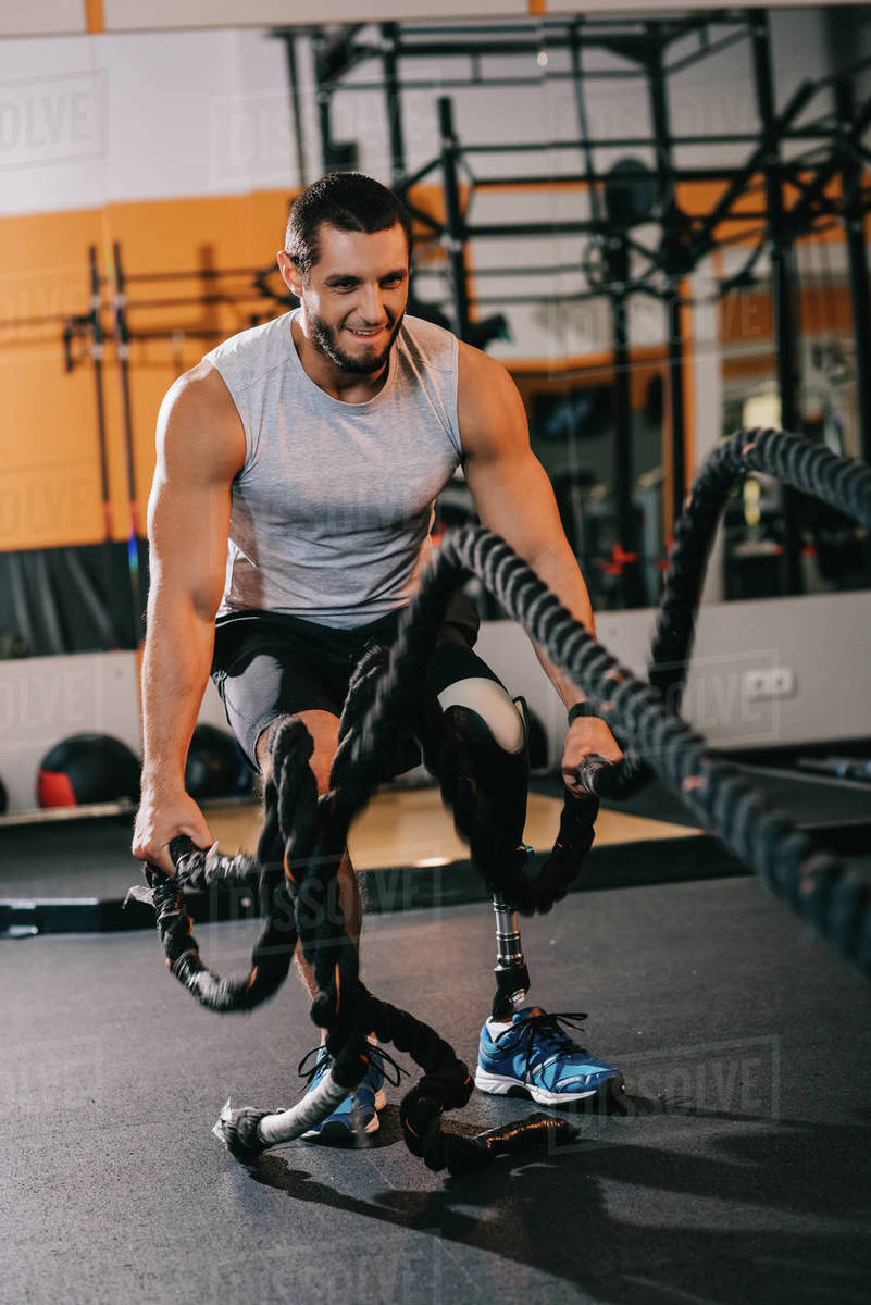 Handsome young sportsman with artificial leg working out with ropes at ...