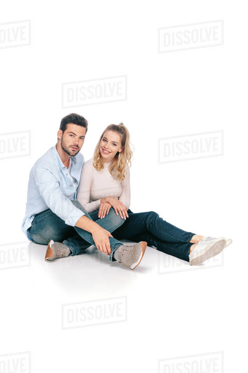 happy young couple sitting together and smiling at camera isolated on ...