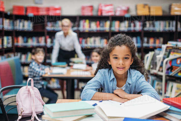 beautiful african american schoolgirl with pile of books at library ...