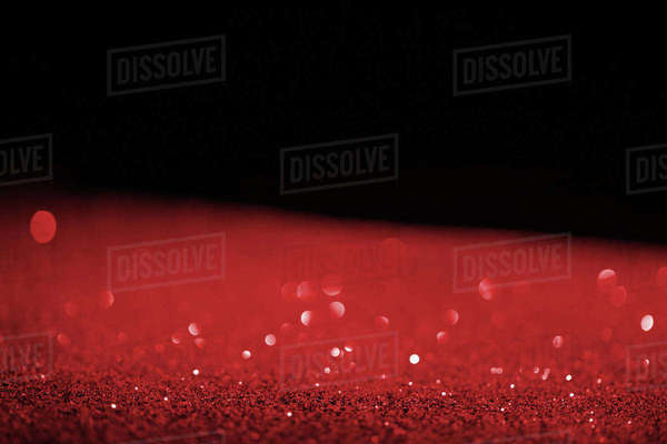 Blurred red glowing glitter on black background - Stock Photo - Dissolve