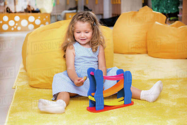 Happy adorable child sitting on carpet and playing with toy in ...