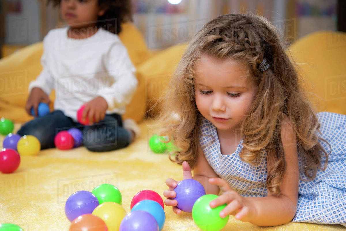 Multicultural kids playing with colorful balls on carpet in ...