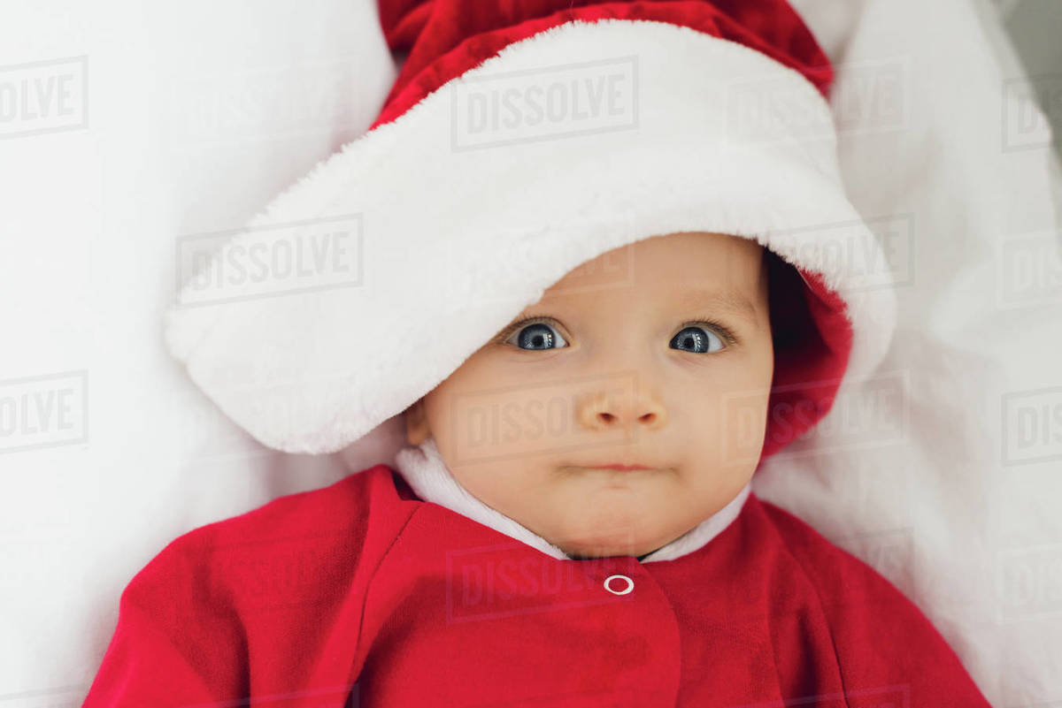 Close-up portrait of adorable little baby in santa suit lying in bed ...