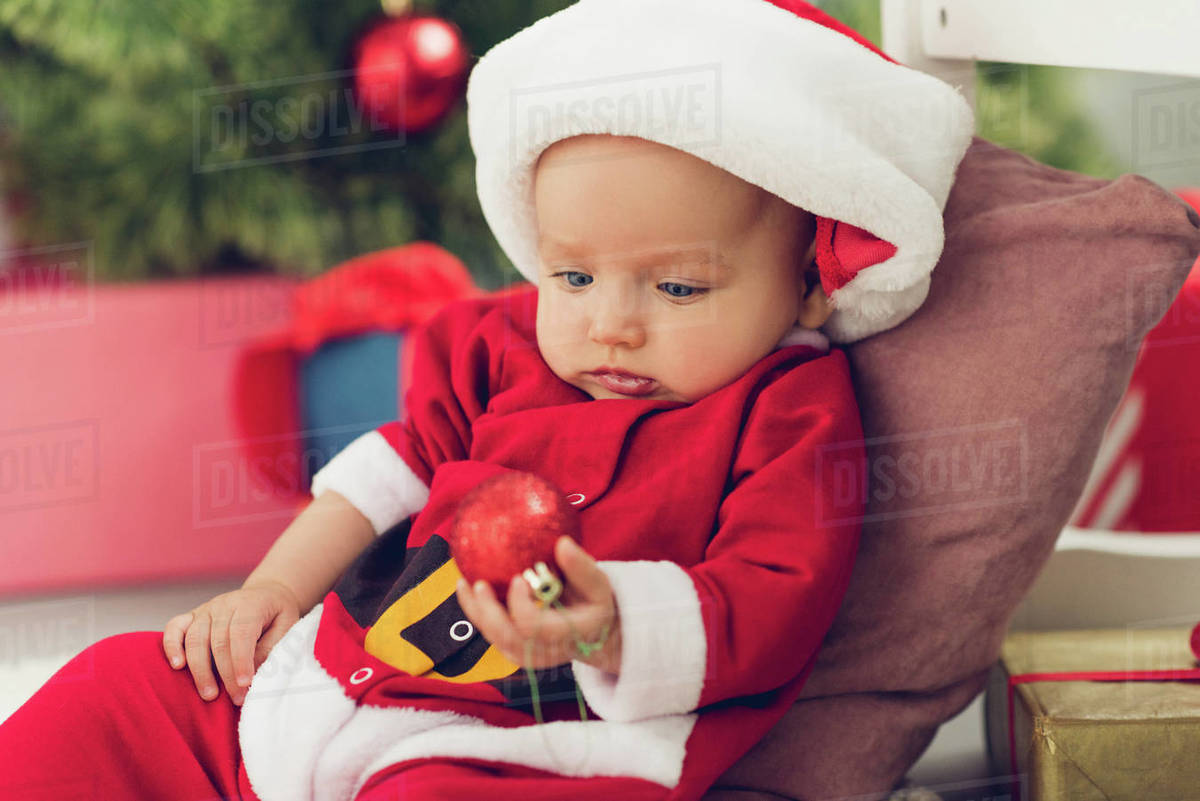 Adorable little baby in santa suit holding christmas bauble - Stock ...
