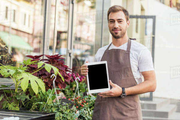 Handsome florist holding tablet with blank screen near flower shop and ...