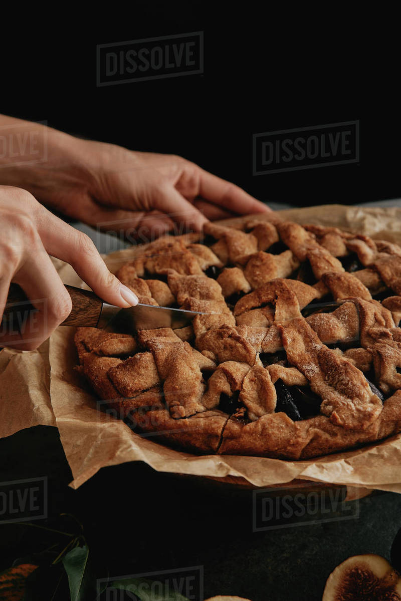 cropped shot of woman cutting pie on baking paper with knife - Royalty ...