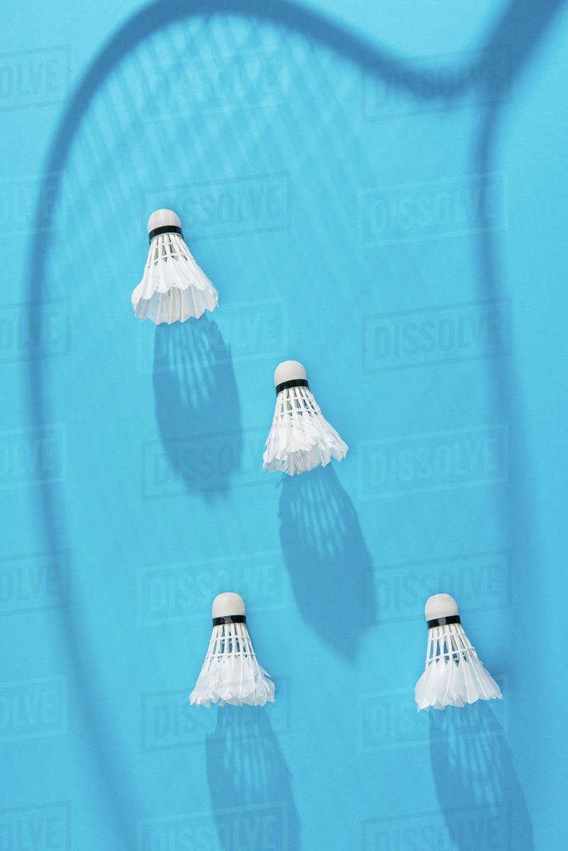 top view of white shuttlecocks and badminton racket shadow on blue ...