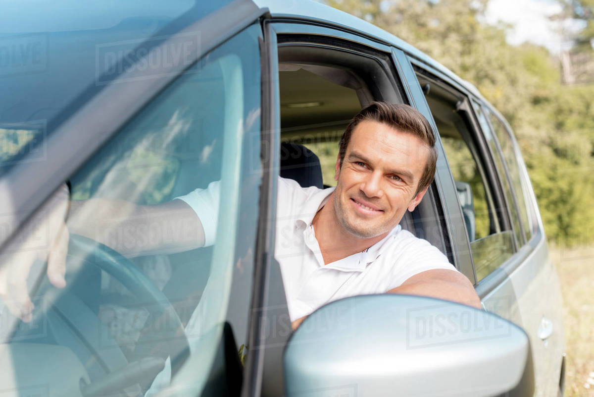 happy man looking out window while driving car in field - Stock Photo ...