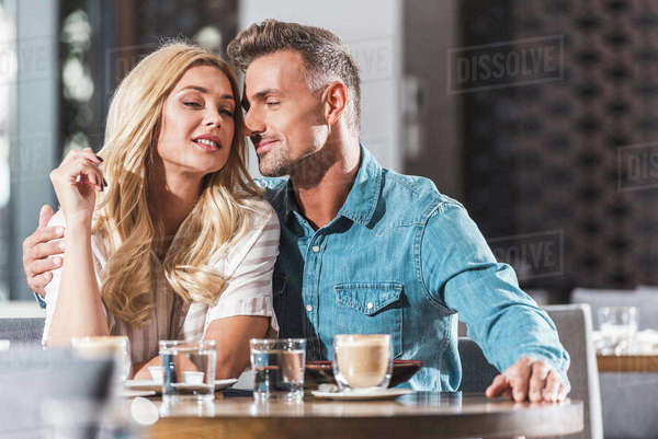 Affectionate couple cuddling at table in cafe during date - Royalty ...