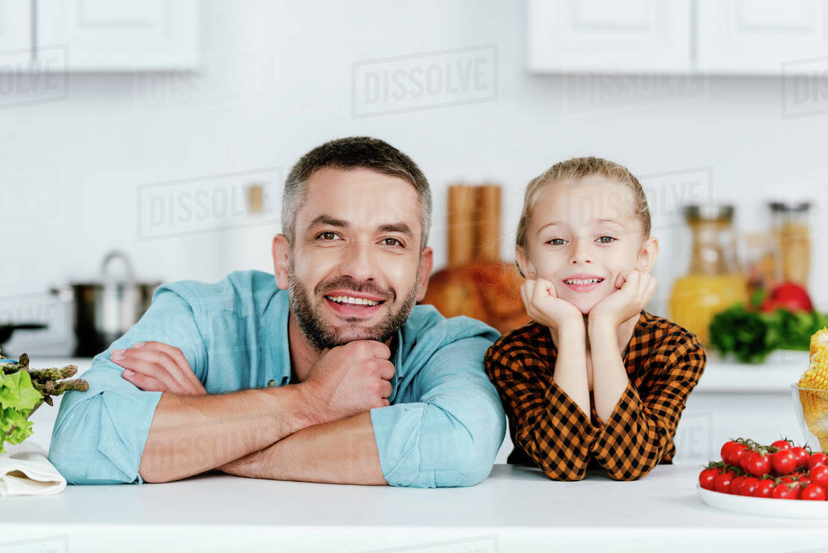 Father and adorable little daughter looking at camera on kitchen ...
