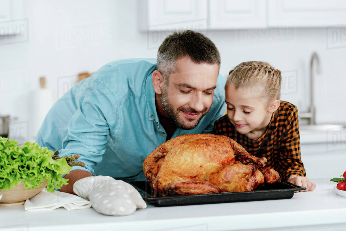 Happy father and daughter sniffing freshly baked thanksgiving turkey ...
