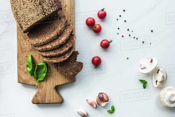 Flat lay with cut bread on wooden cutting board, black pepper and ...
