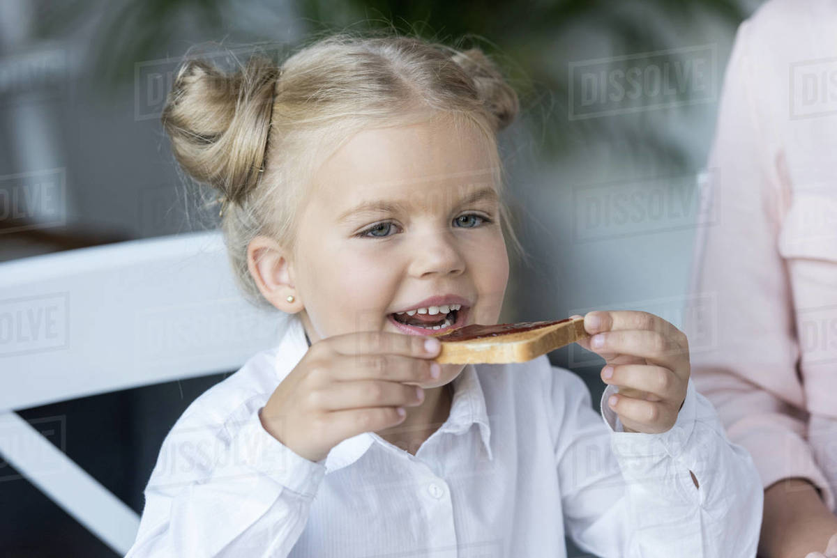 Adorable little girl eating toast with jam at breakfast - Royalty-free ...