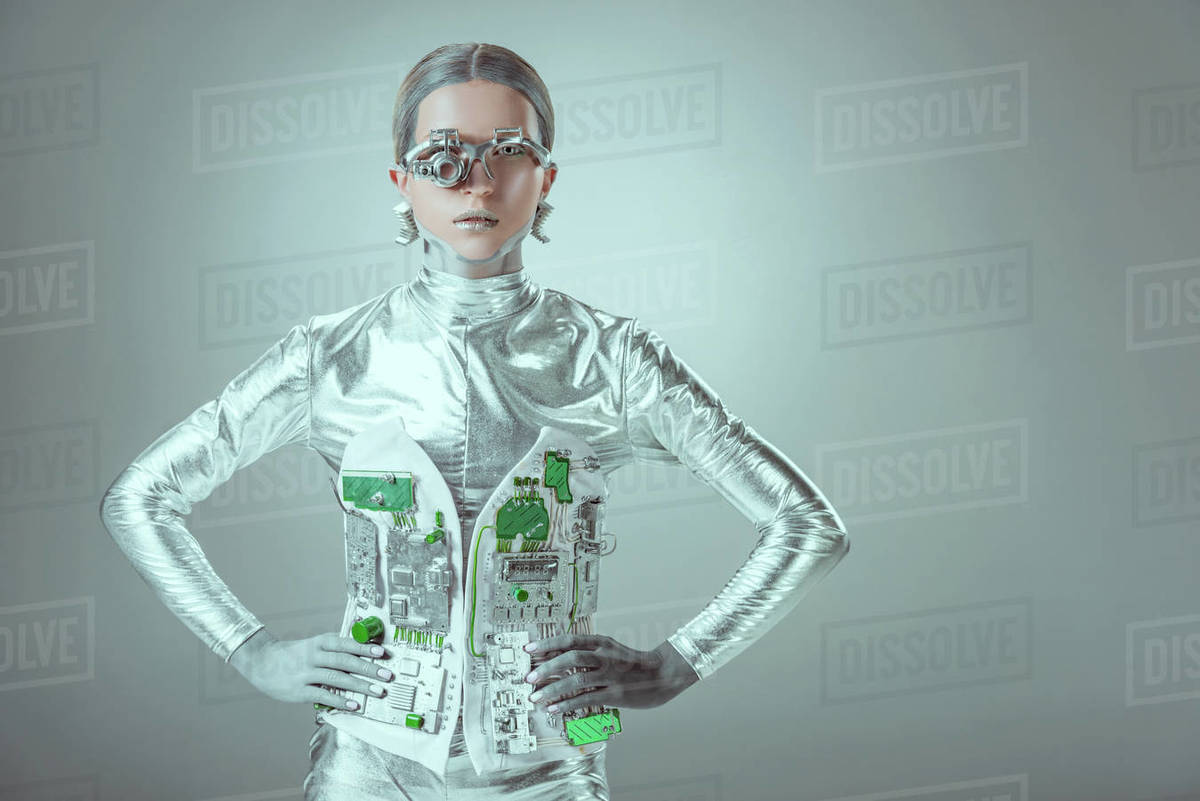 Futuristic silver cyborg standing with hands on waist and looking at ...