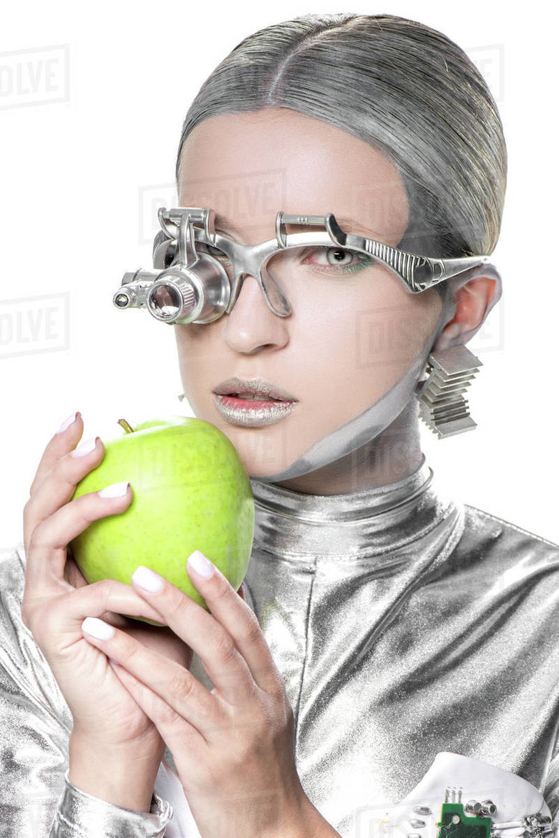 Portrait of silver cyborg holding apple and looking at camera isolated ...