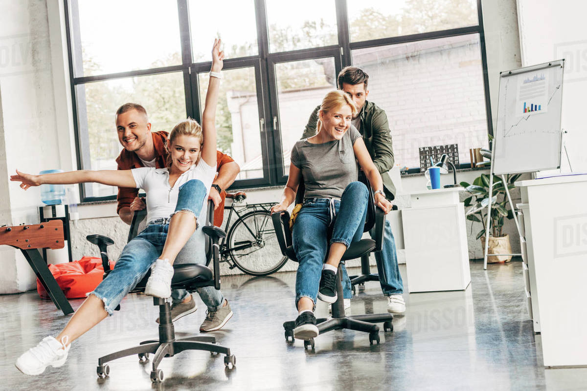 group of young business people riding chairs at modern office - Royalty ...