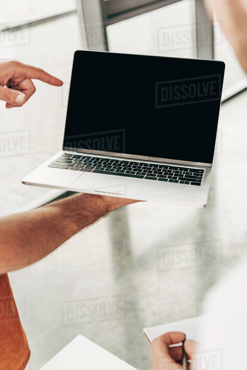 cropped shot of business people pointing at blank laptop screen during ...