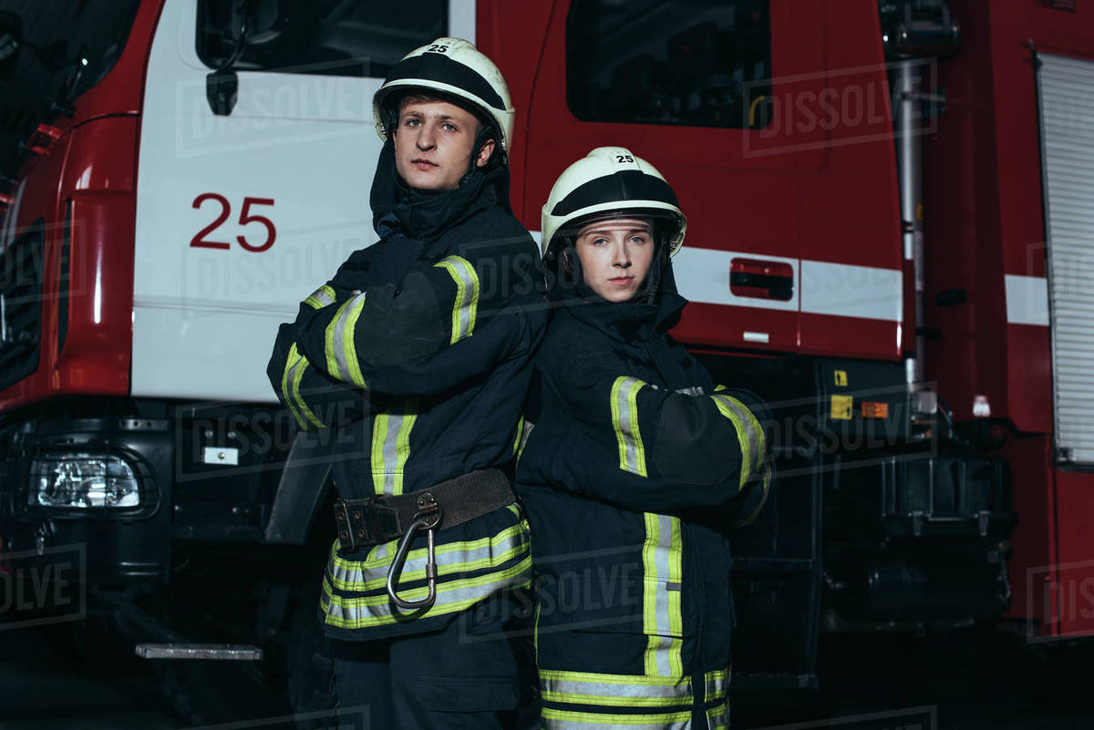 portrait of firefighters in fireproof uniform and helmets with arms ...