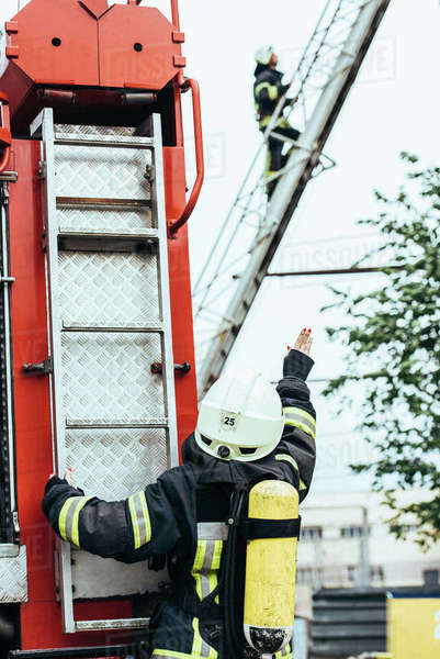 back view of female firefighter with fire extinguisher on back ...