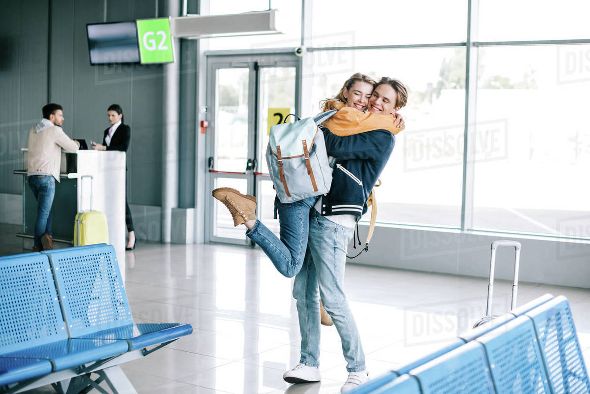 Cheerful young couple hugging in airport terminal - Royalty-free Stock ...