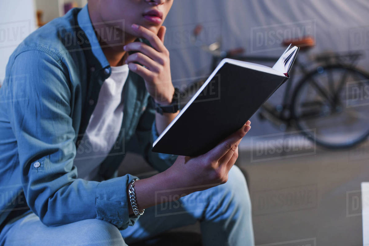 Cropped shot of thoughtful young man reading book at home - Royalty ...
