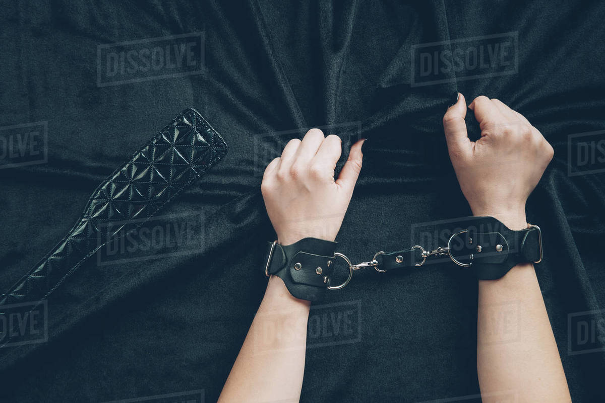 Cropped shot of woman in leather handcuffs holding black fabric - Stock ...
