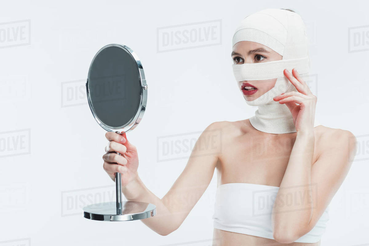 Woman with bandages over head looking at mirror isolated on white ...